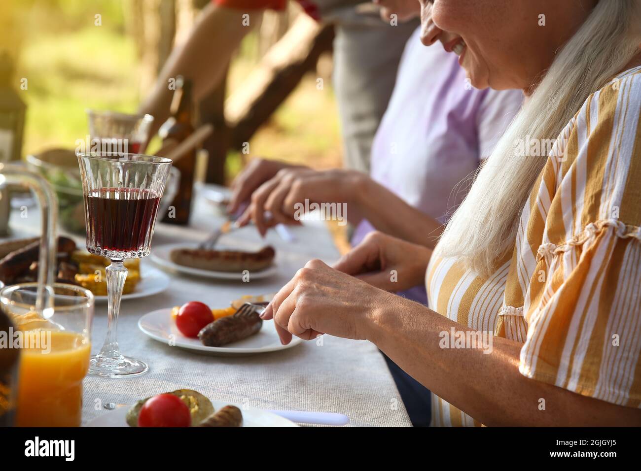 Mature woman eating grilled food at barbecue party Stock Photo - Alamy