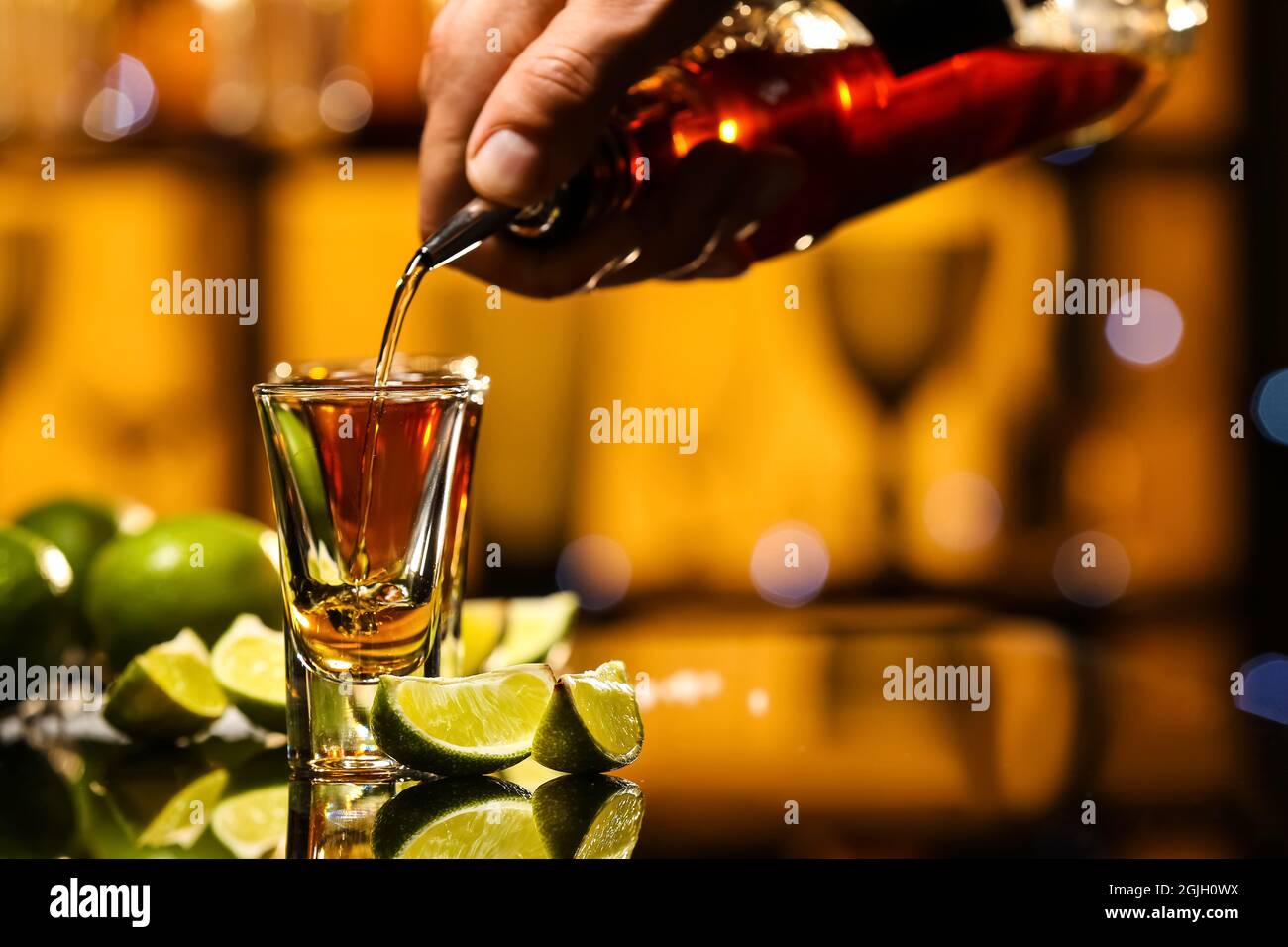 Bartender pouring tasty tequila into glass at table in bar Stock Photo ...