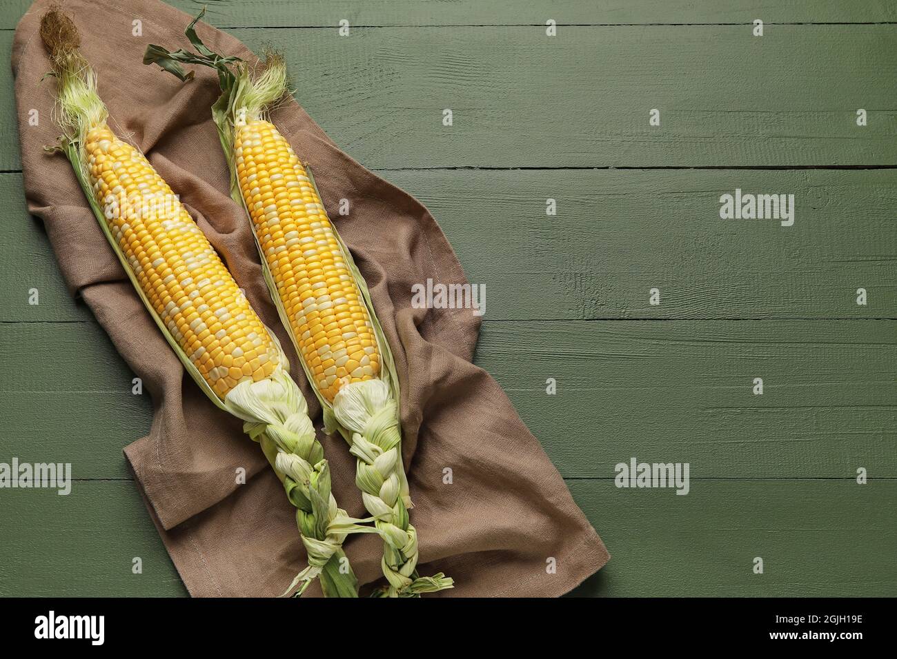 Fresh corn cobs on color wooden background Stock Photo - Alamy