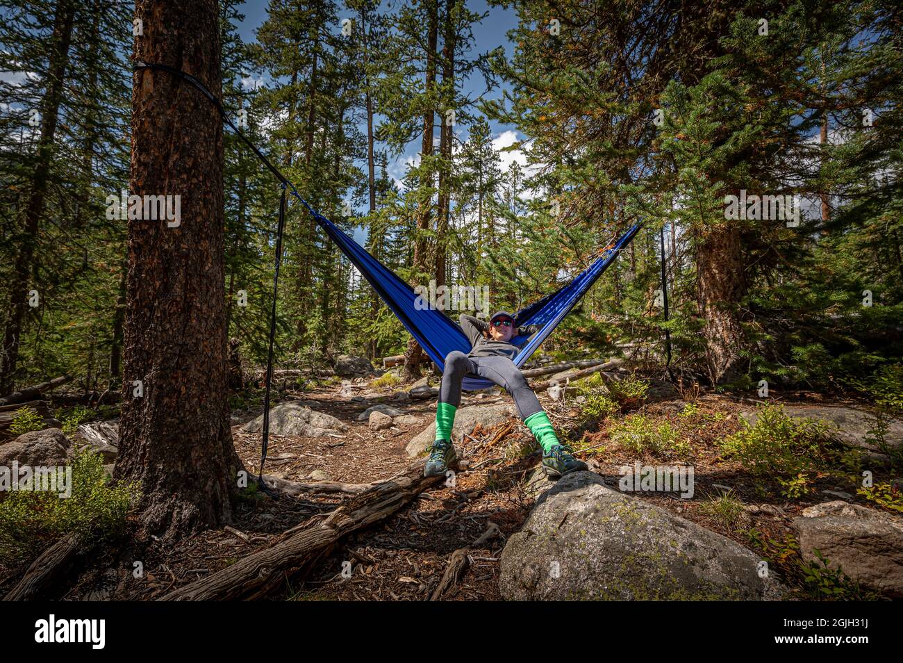 A backpacker relaxes on a hammock at a campsite in Rocky Mountain ...