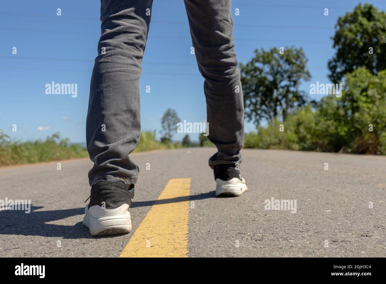 Men`s feet standing on asphalt road with yellow marking lines. Man ...