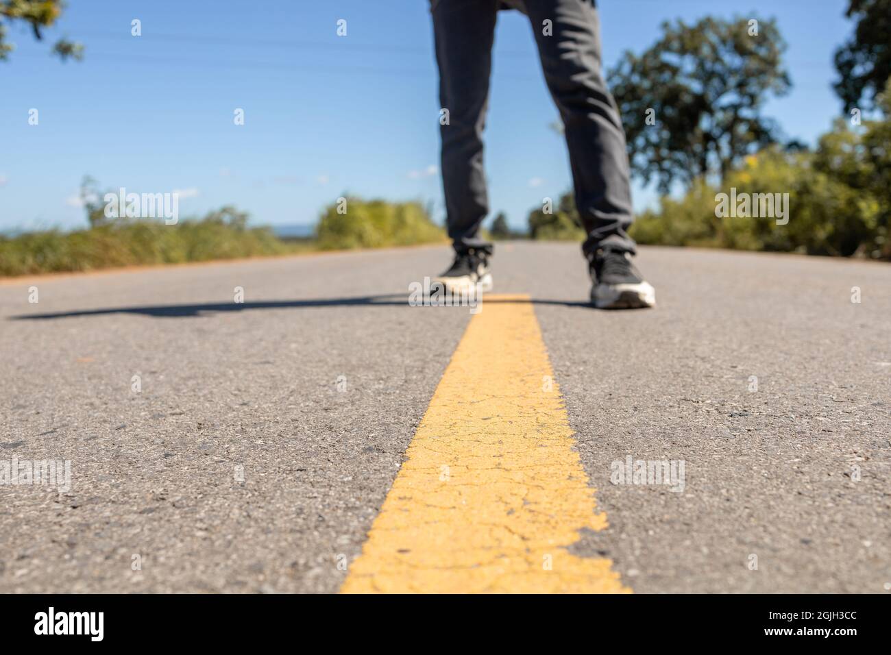 Men`s feet standing on asphalt road with yellow marking lines. Man ...