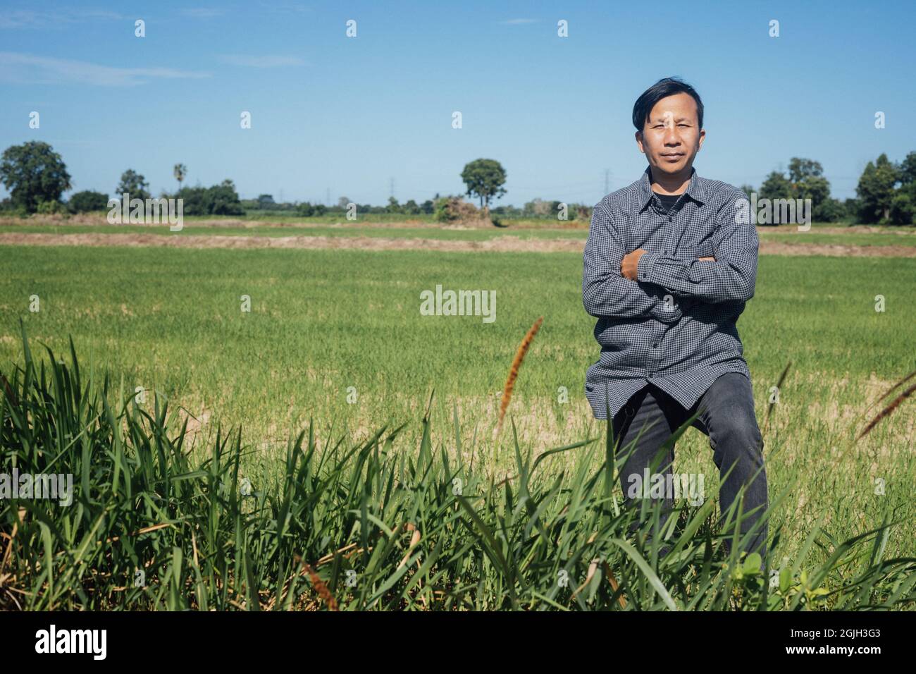 A modern farmer stands proud of his farmland in bright sunlight during ...