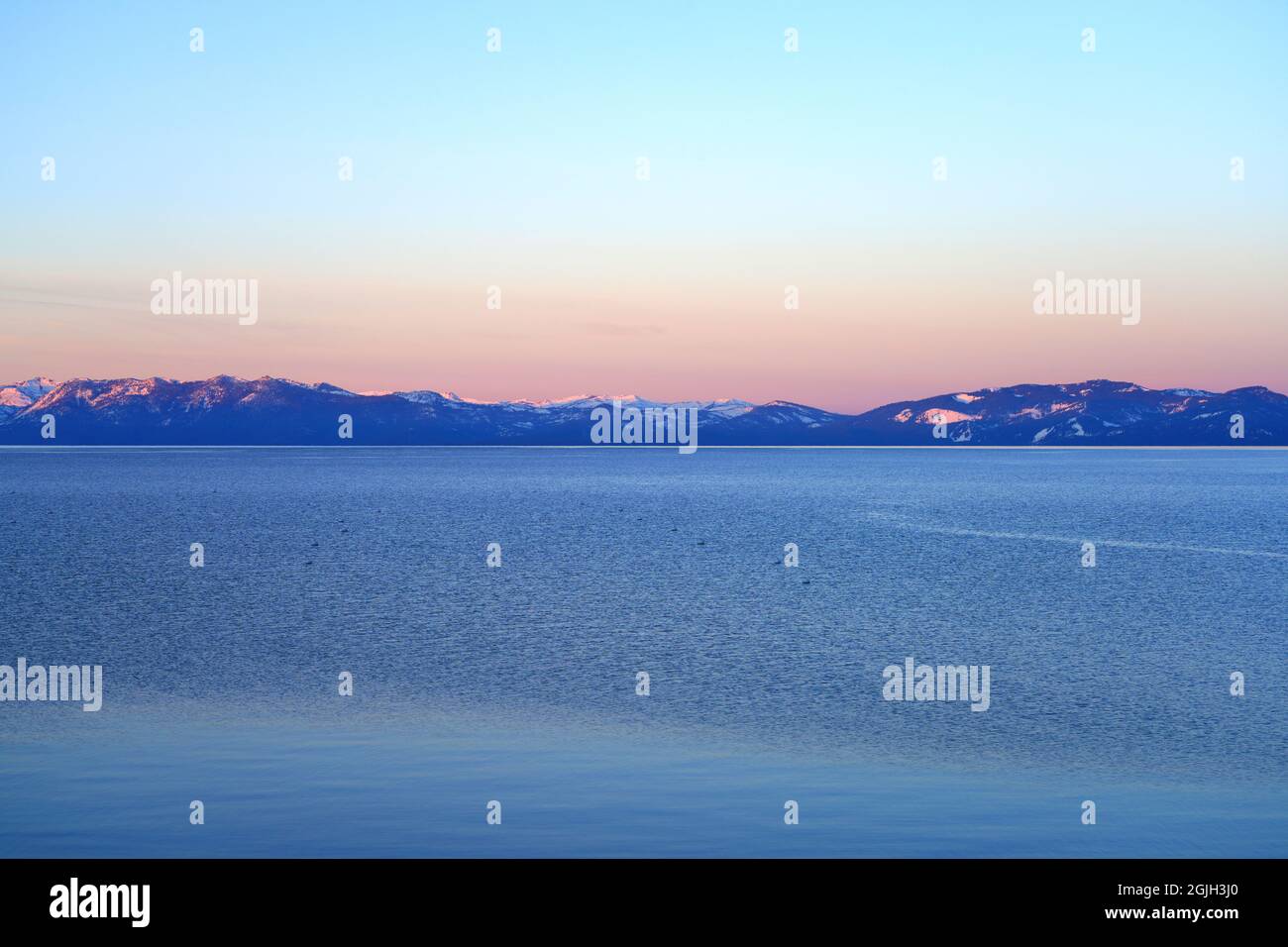 Landscape view of a sunset sky over Lake Tahoe with snow-covered ...