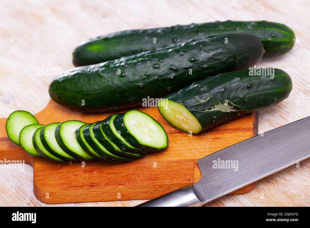 Ripe cucumbers and knife on wooden cutting board Stock Photo - Alamy