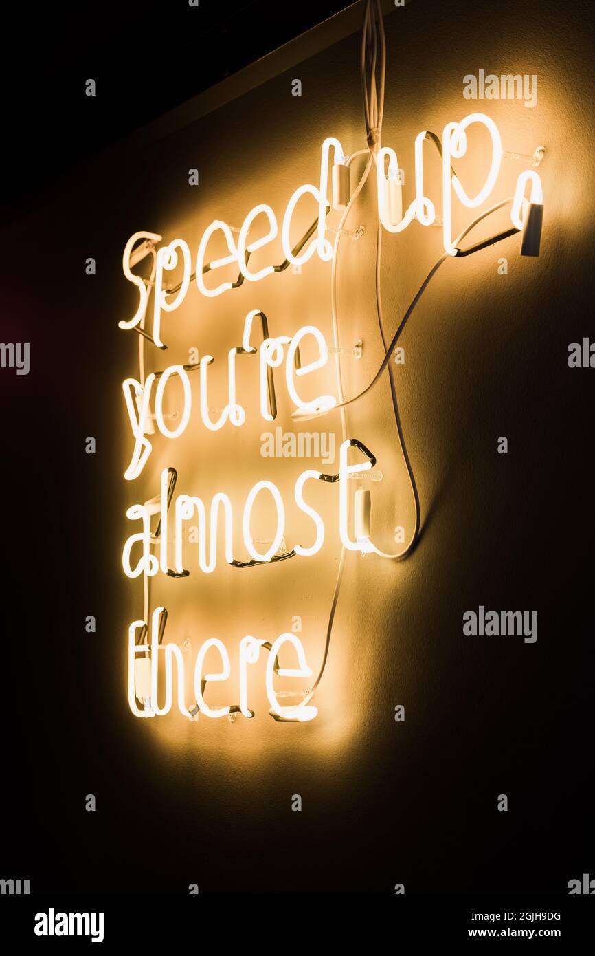 Neon yellow lettering on the wall speed up, you are almost there. High ...