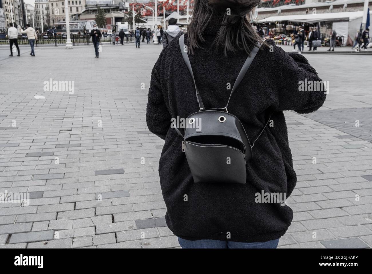 Woman outdoors wearing a black jacket and a black leather backpack ...