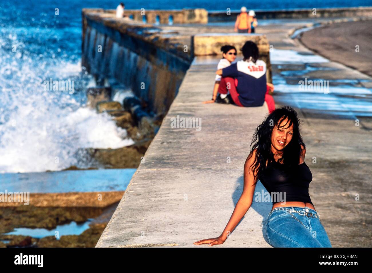 Cuban girl posing, and couple together on sea wall, Malecon, Havana ...