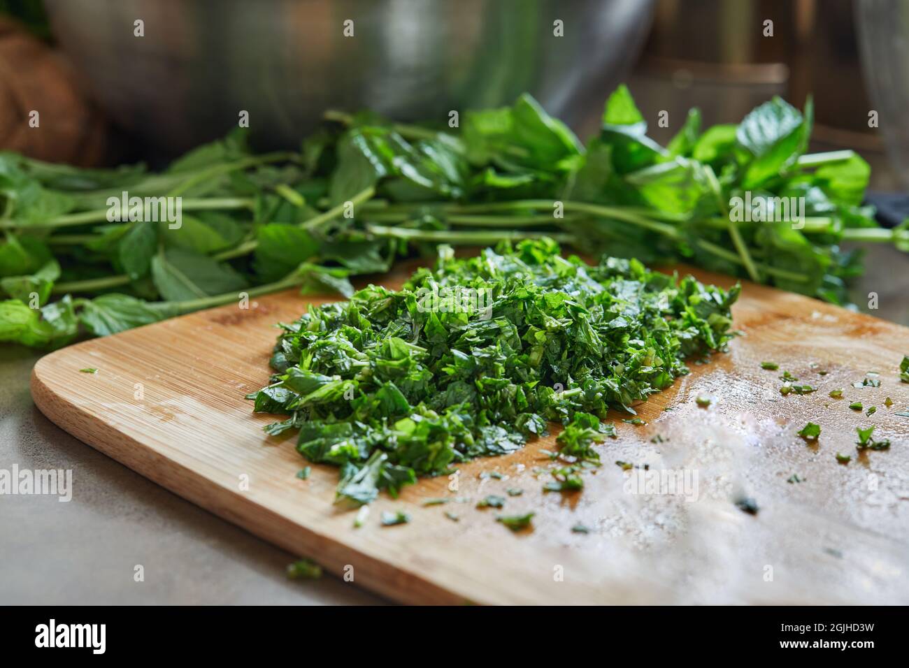 Chef cuts basil according to the recipe for cooking on wooden board in ...