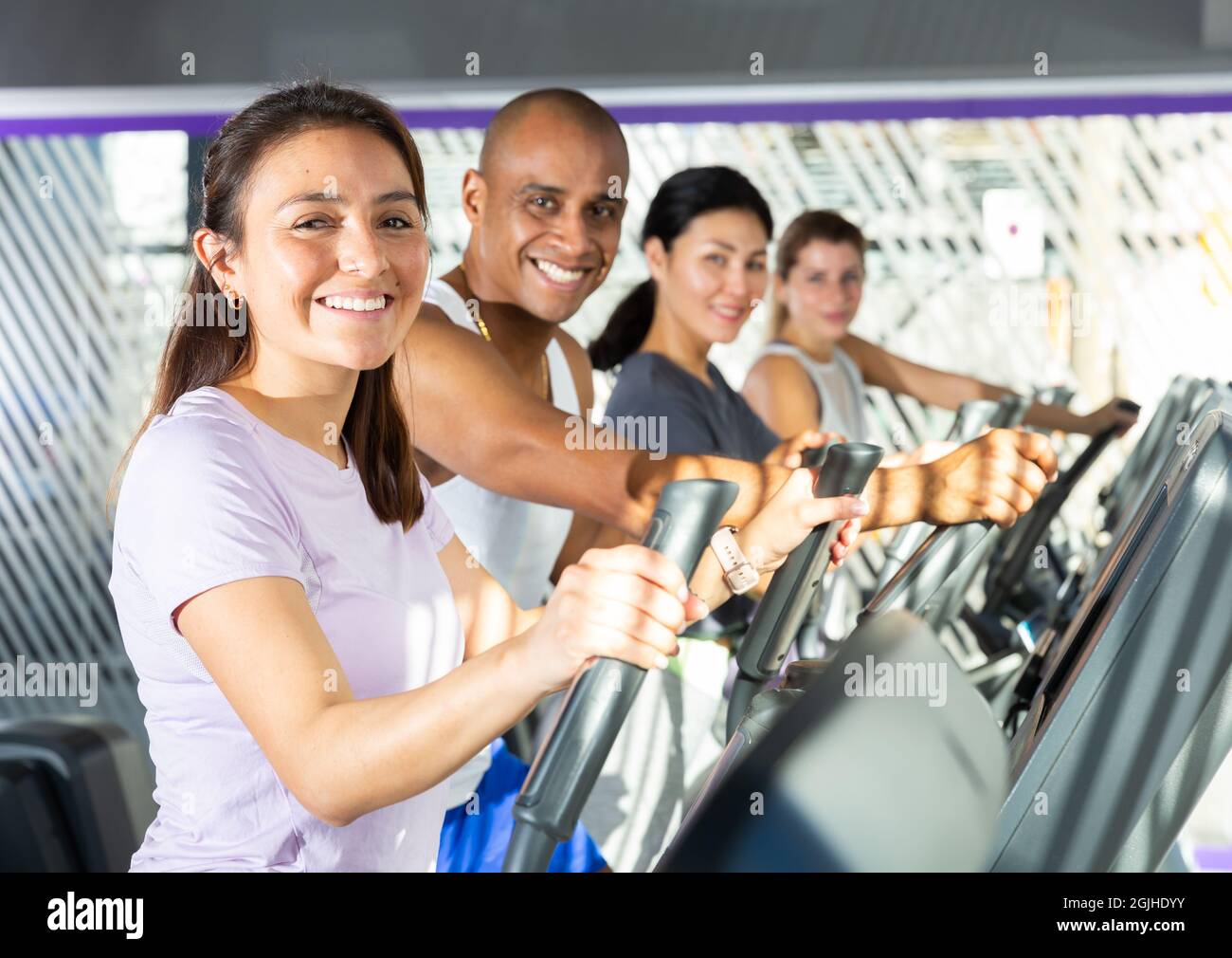 Athletic people running on elliptical trainer in fitness club Stock Photo - Alamy