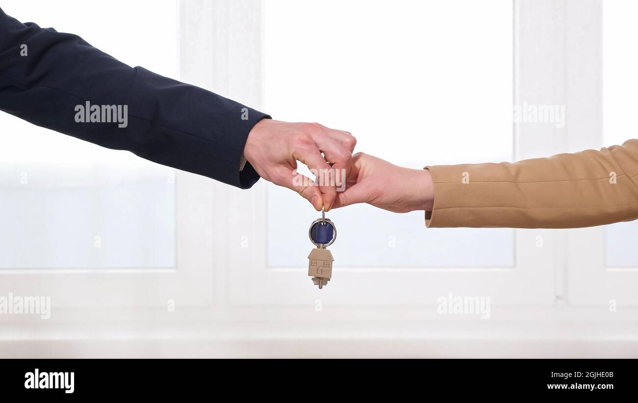 Man and woman shake hands giving over keys to apartment Stock Photo - Alamy