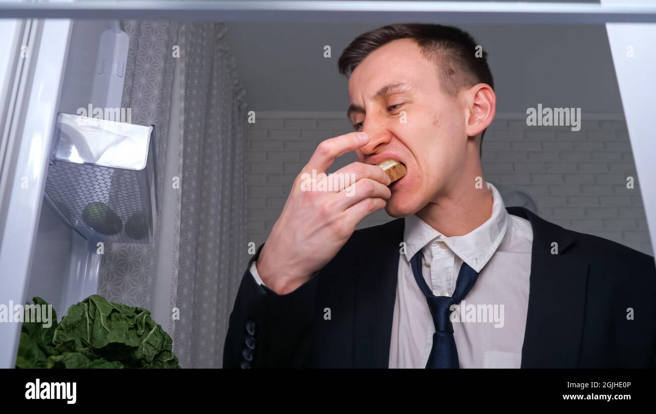 Tired businessman takes sandwich with butter from fridge Stock Photo ...