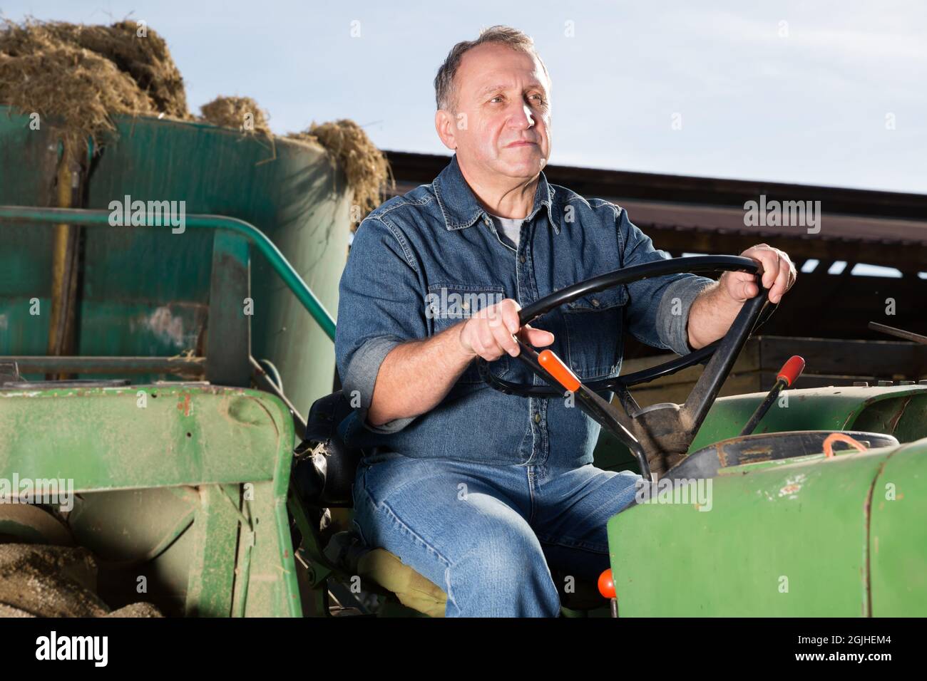 Confident male farm owner driving tractor Stock Photo - Alamy