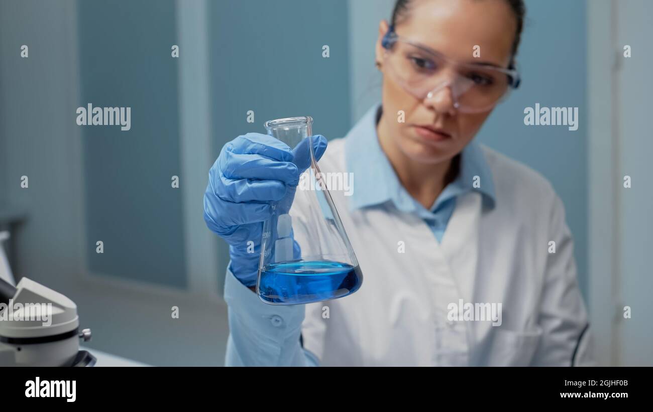 Portrait of microbiology doctor analyzing chemical beaker in laboratory ...