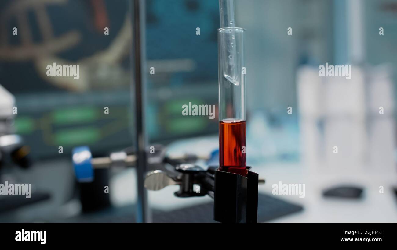 Close up of test tube filled with blood or dna liquid connected to ...