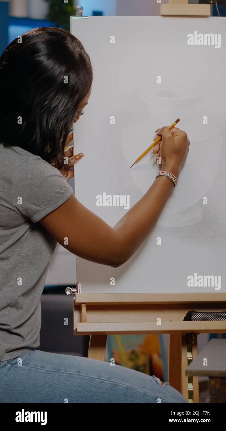 Woman of african american ethnicity drawing vase on white canvas and ...