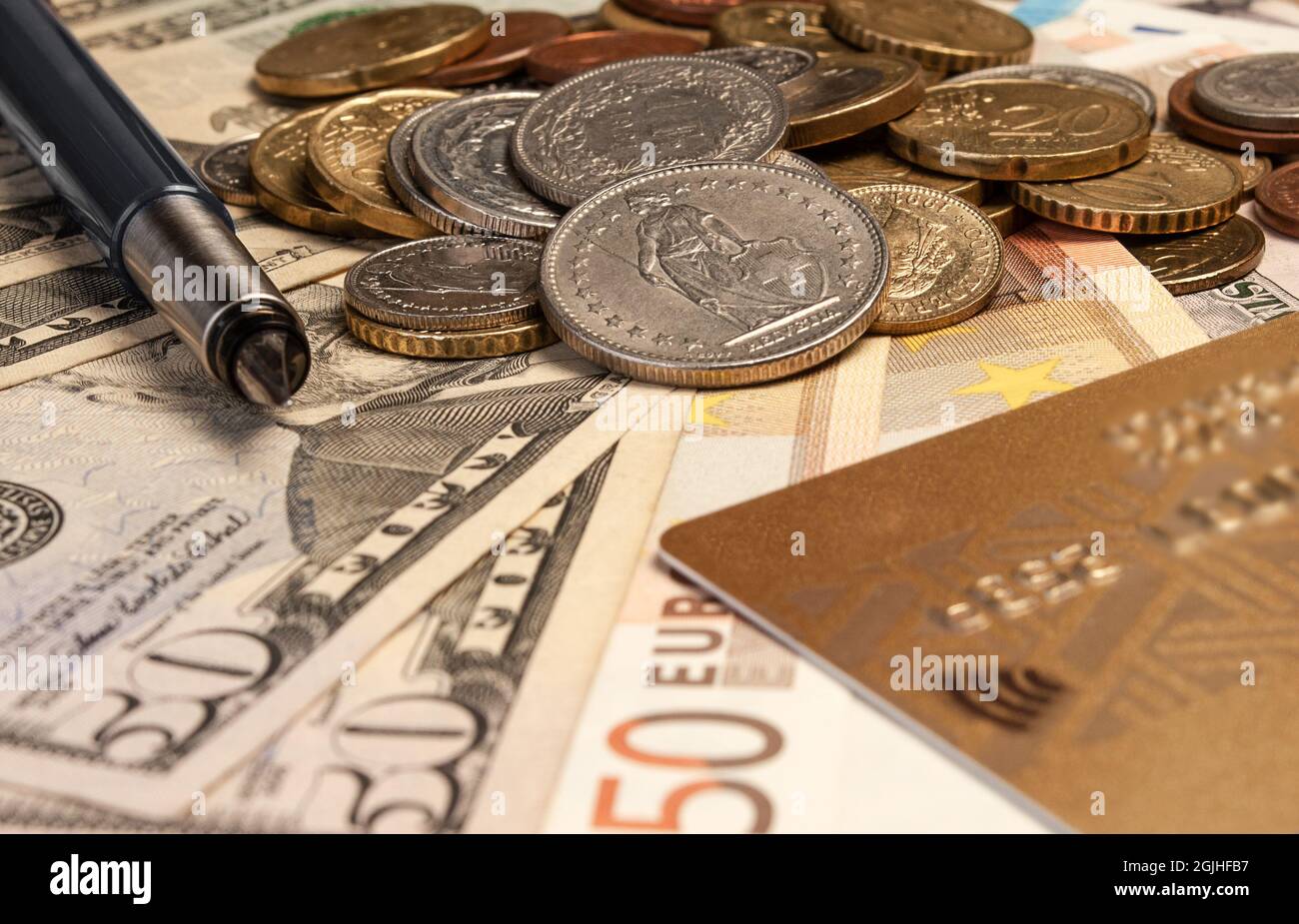 credit card and ink pen lying on a background of banknotes and coins of ...