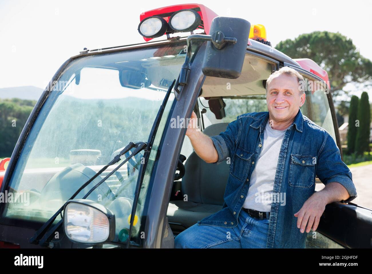 Smiling male farm owner driving tractor Stock Photo - Alamy