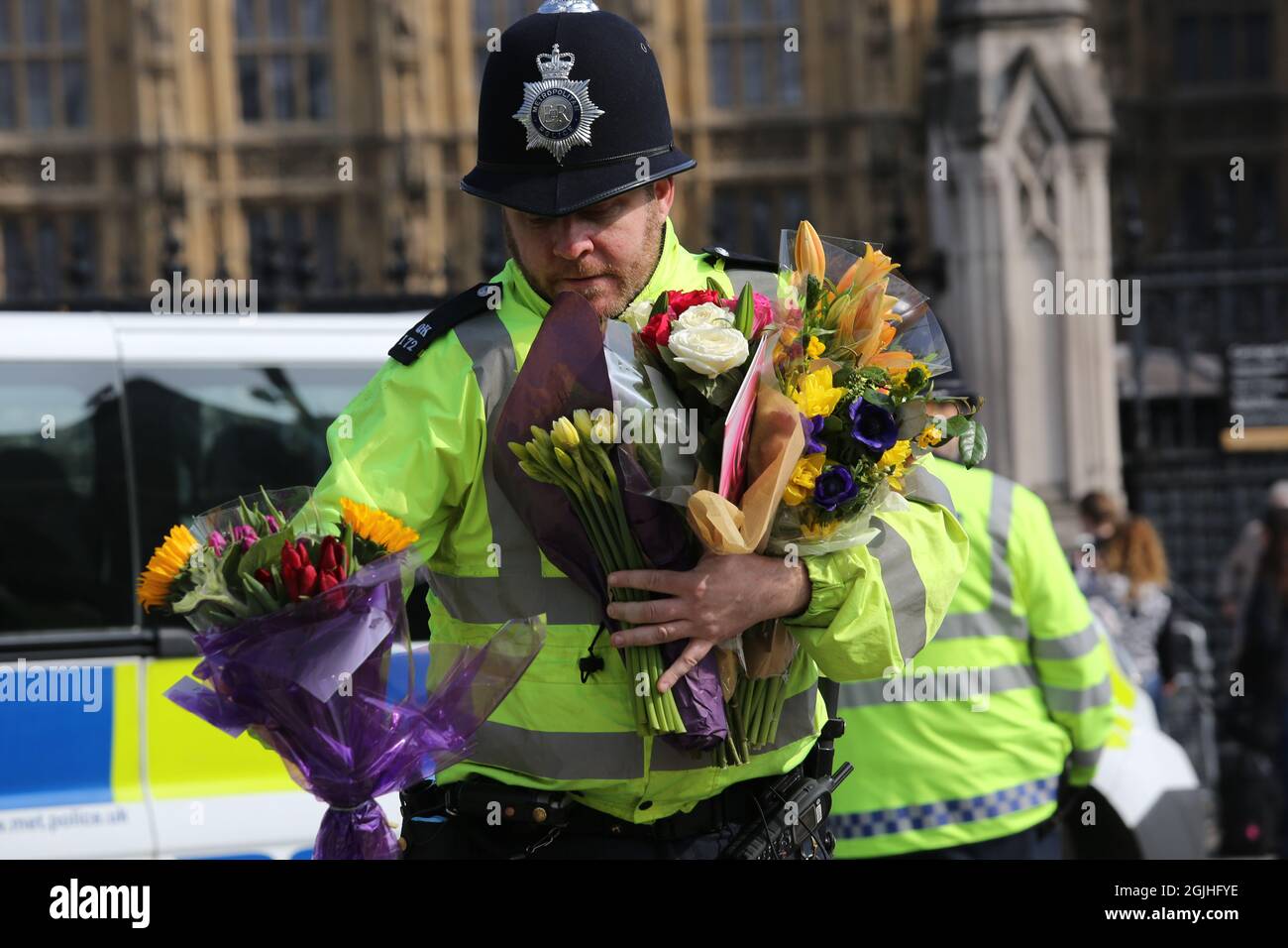 A police officer carries flowers across the road at Westminster in the ...