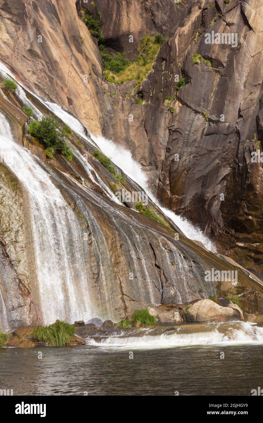 The river flows abruptly into a small lake and over a drop, creating a ...