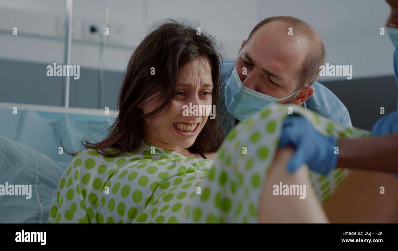 Pregnant young woman giving birth to child feeling tired and screaming ...