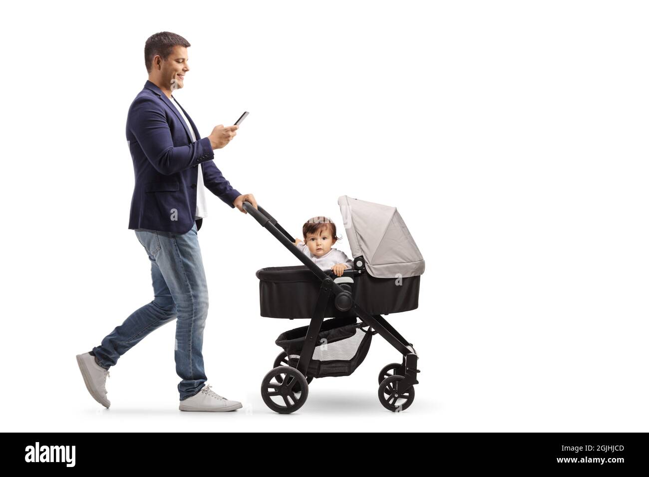 Full length profile shot of a father pushing a baby stroller and typing ...