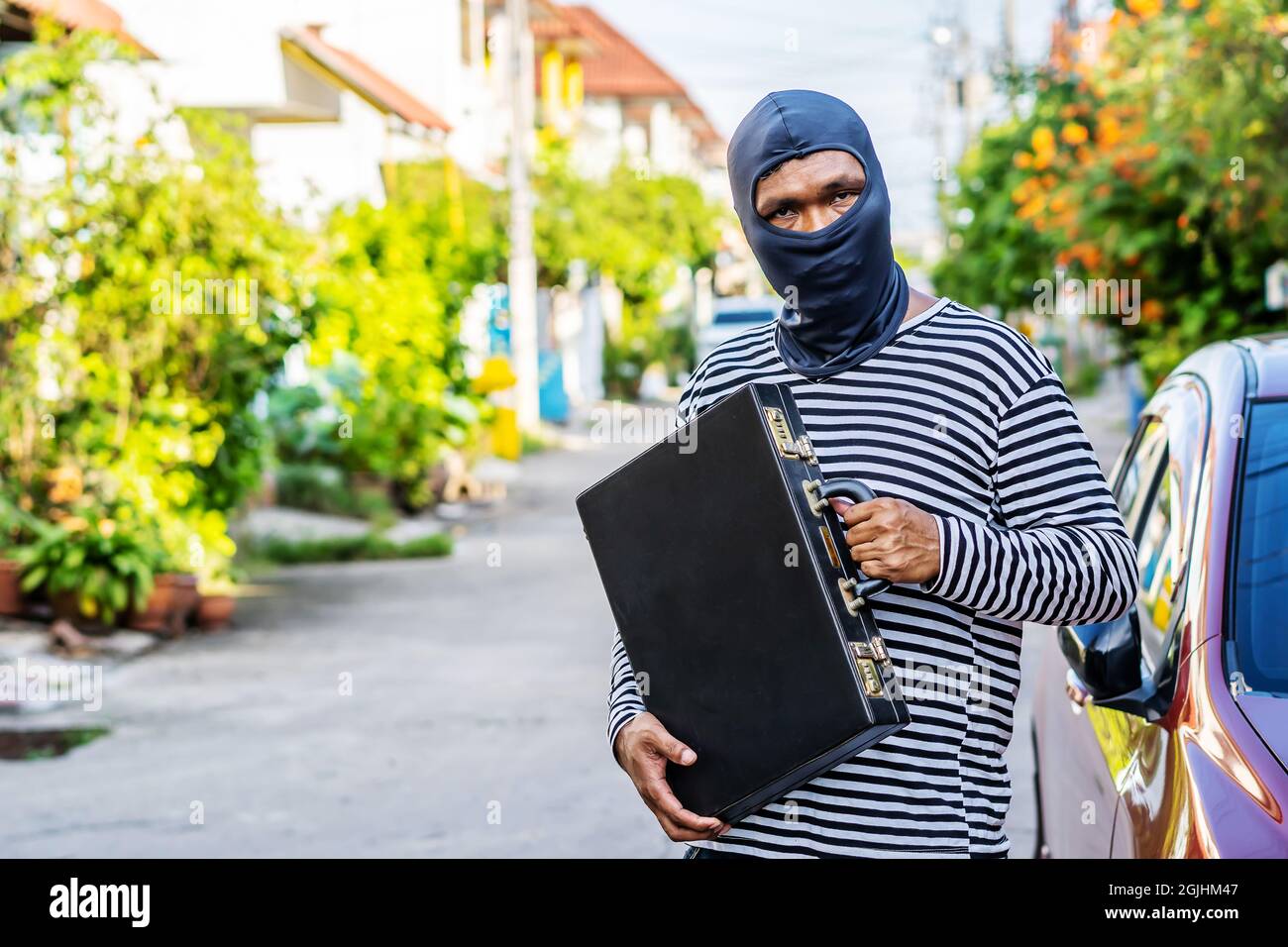 The male thief wears a black mask, smiling happily after stealing ...