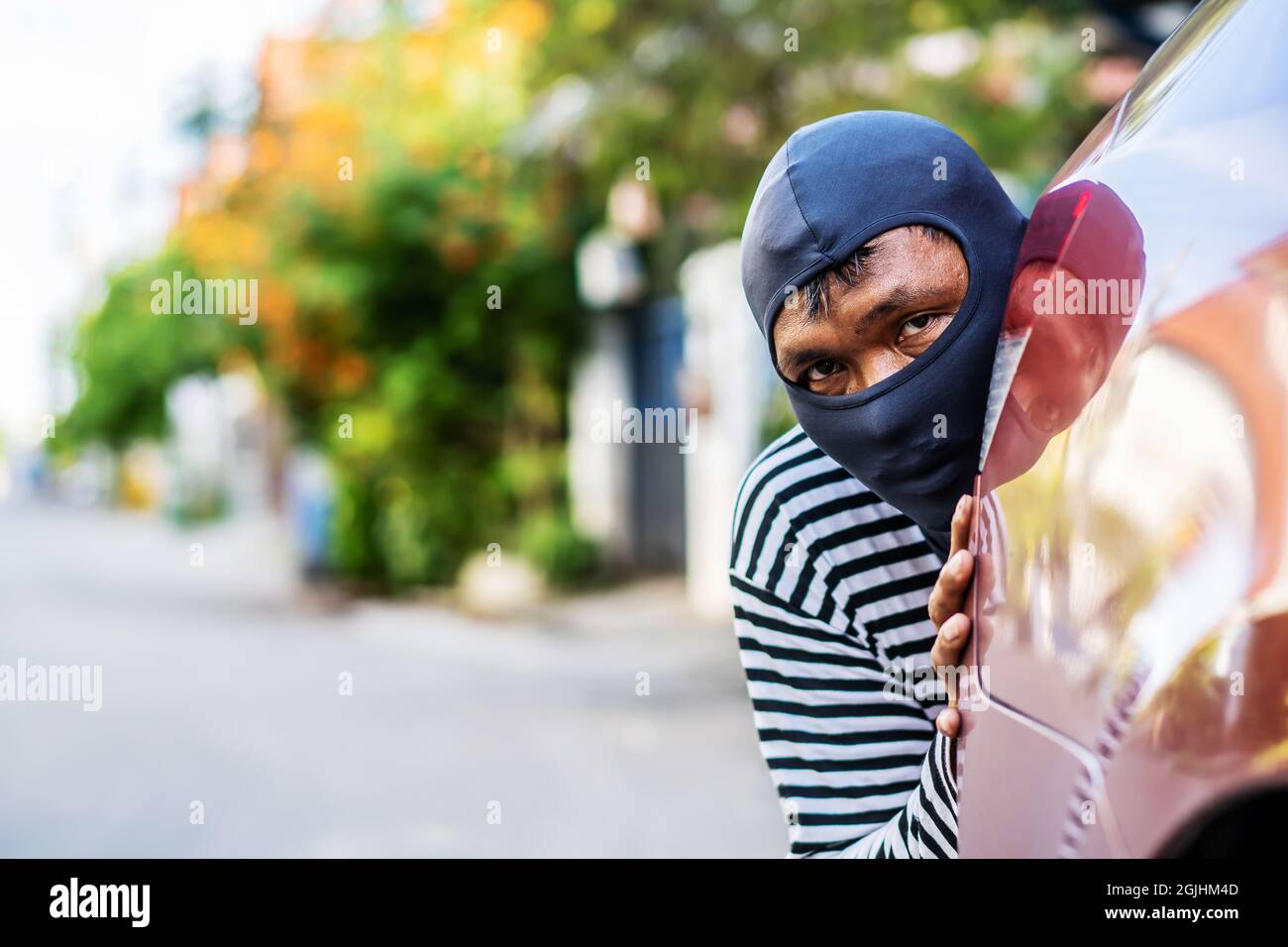 Robber wearing a black head are secretly behind the car to prepare a ...