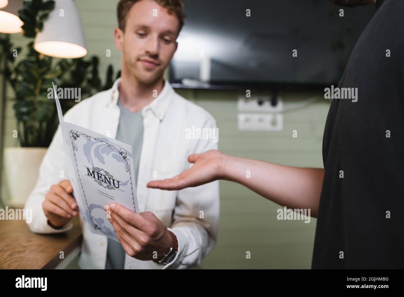 waiter pointing at menu in hands of smiling and blurred customer Stock ...
