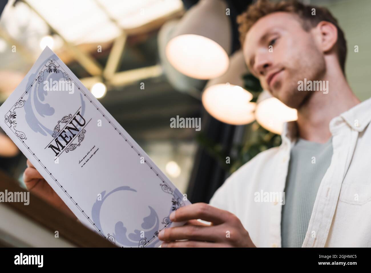 low angle view of curly and blurred man holding menu in cafe Stock ...