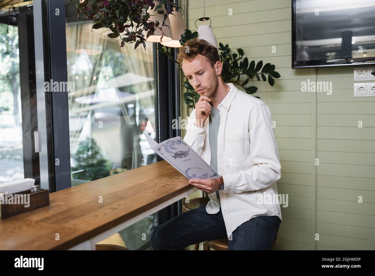 pensive young man looking at menu in cafe Stock Photo - Alamy