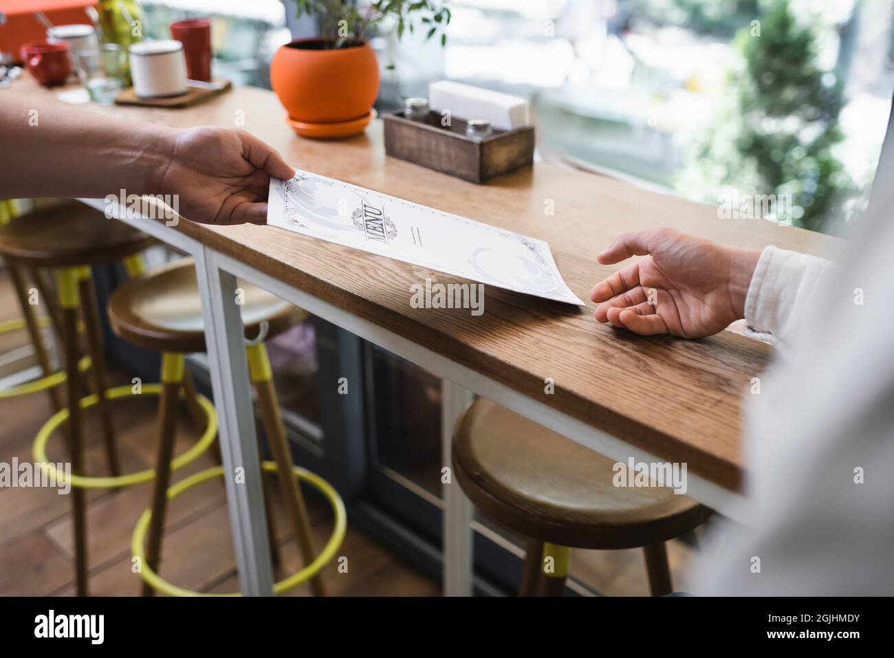 partial view of waiter giving menu to client in cafe Stock Photo - Alamy