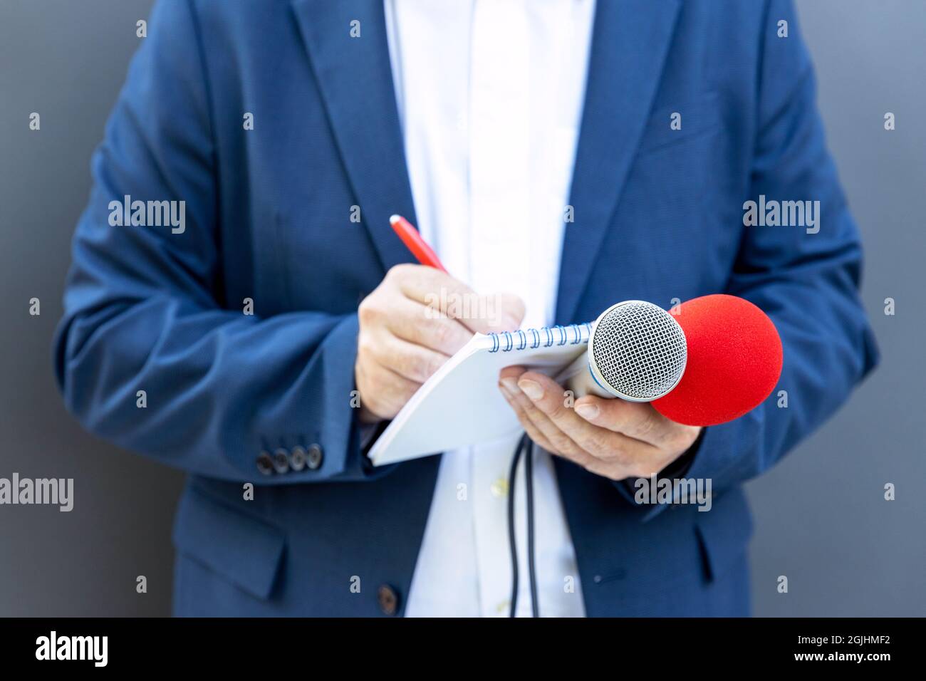 Journalist at media event or press conference, holding microphone ...