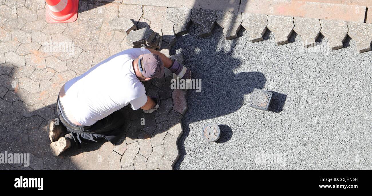 a worker is laying paving stones in gravel Stock Photo - Alamy