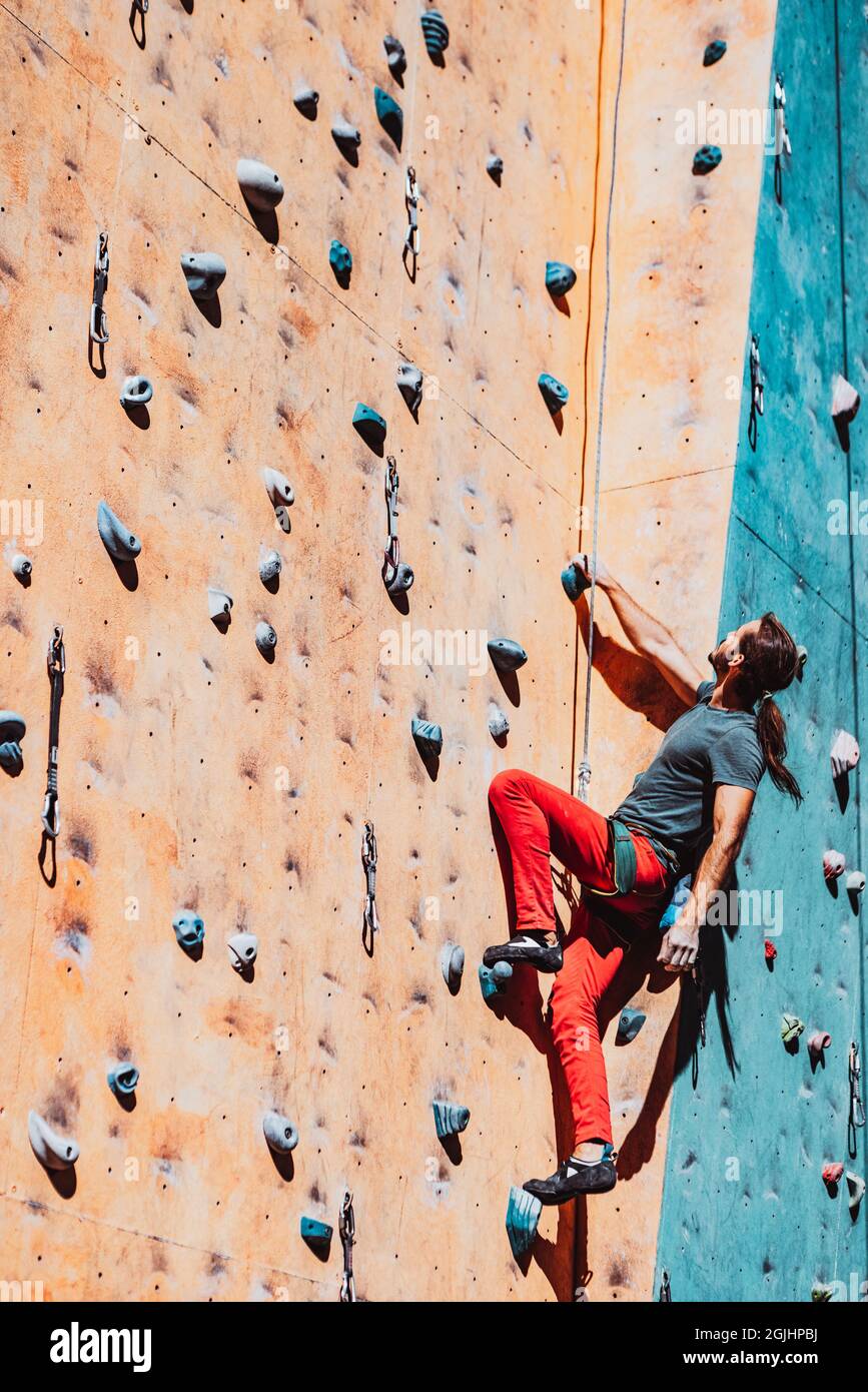 One Caucasian man professional rock climber workouts on climbing wall ...