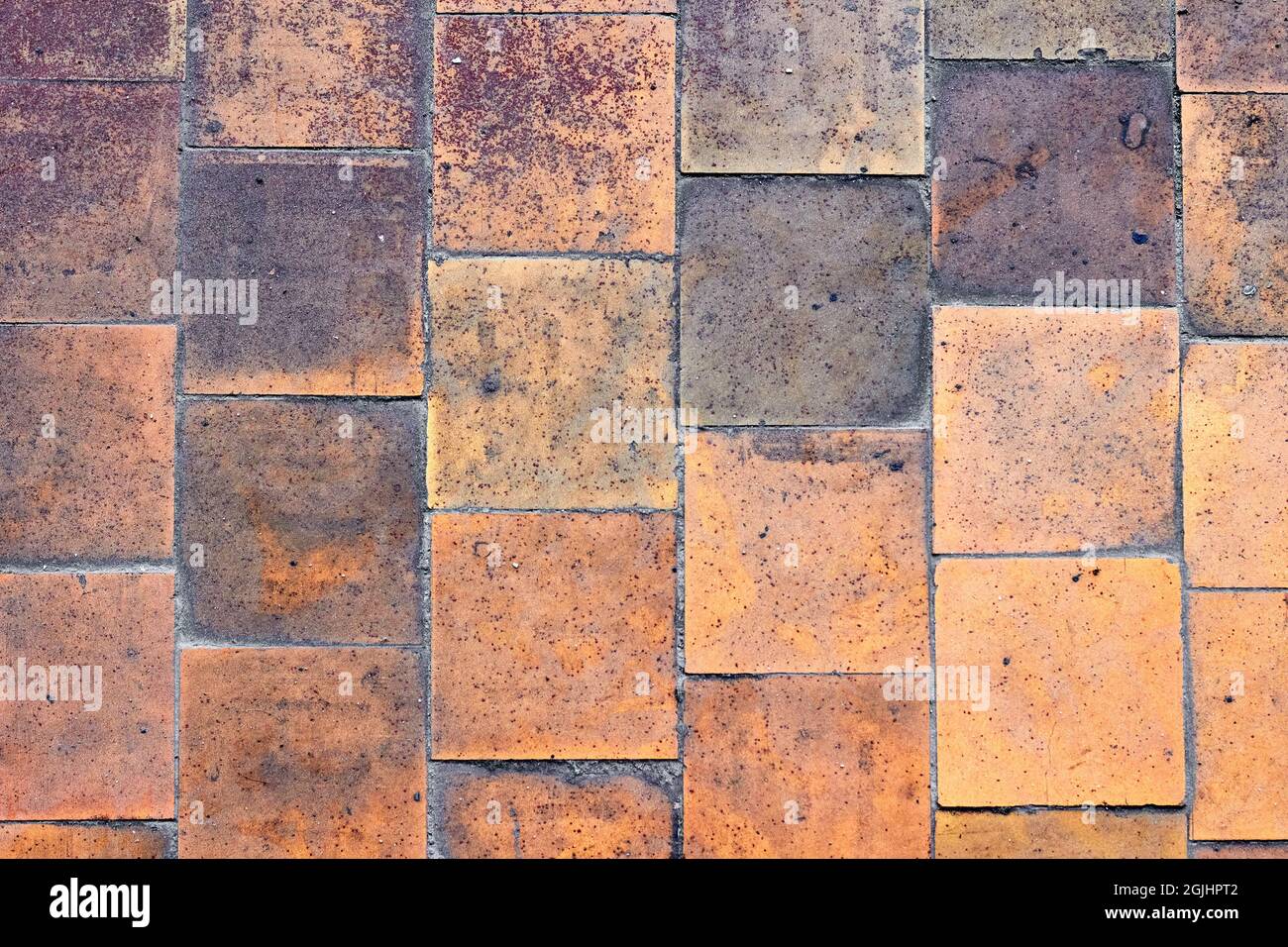 Orange brown purple old shabby worn out floor tiles with damages cracks ...