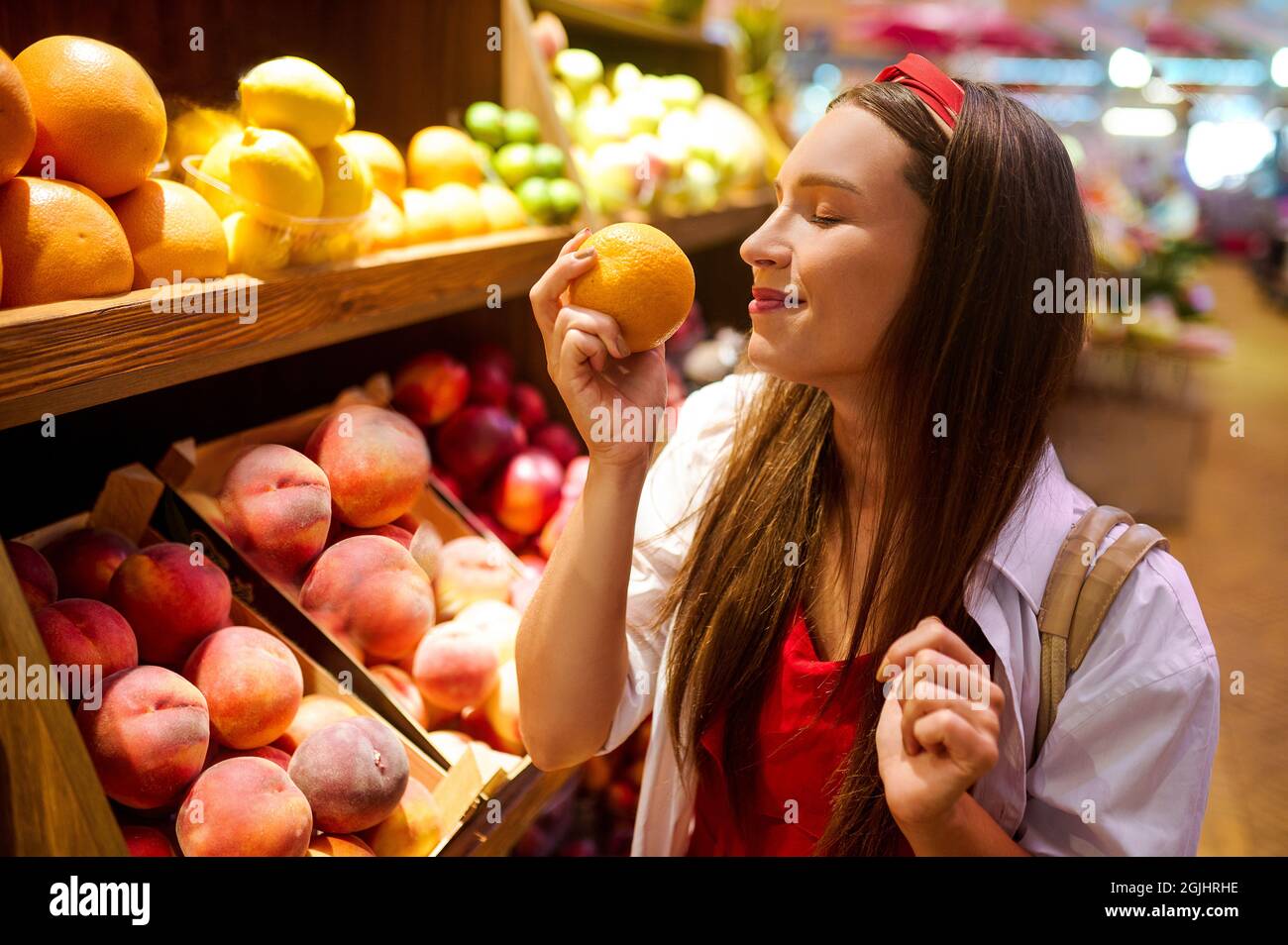 A woman smelling fruits in a store and looking involved Stock Photo - Alamy