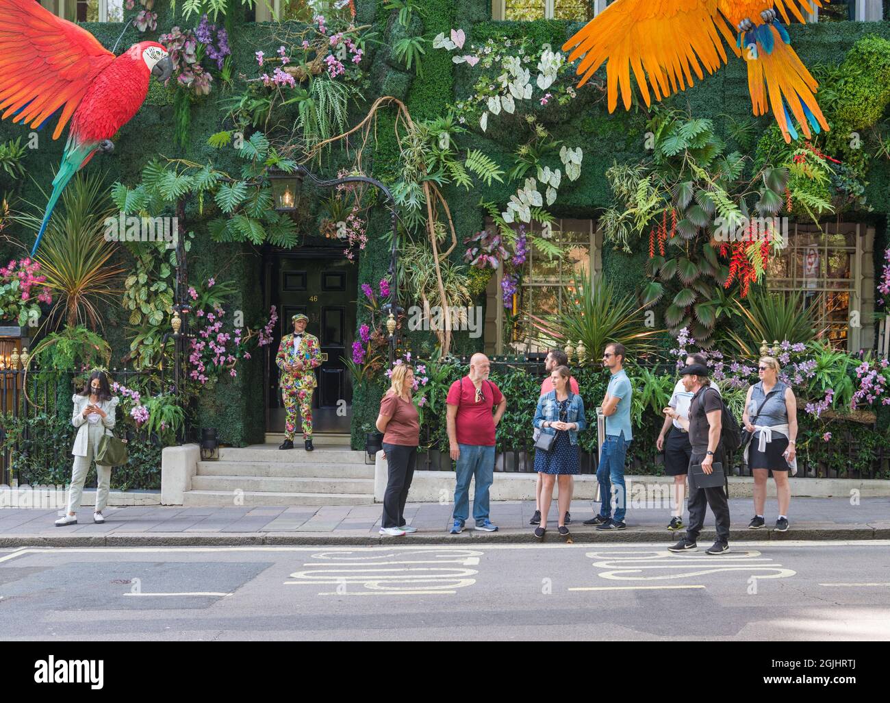 Tour guide and tour group stand on the pavement outside the colourful ...