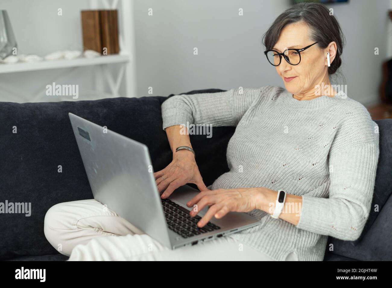 An intelligent mature woman wearing stylish glasses using a laptop ...