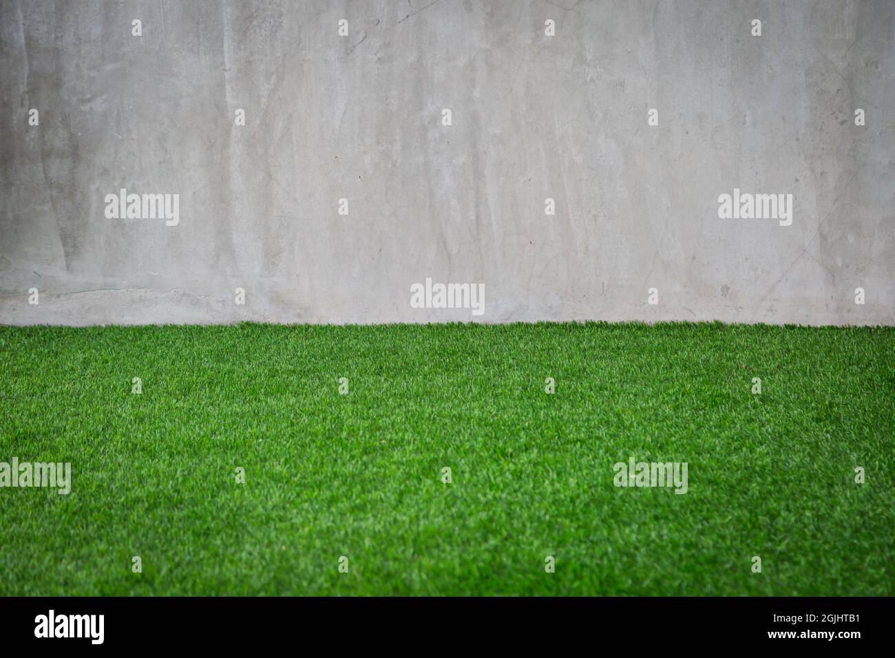 Green grass artificial turf pattern with gray cement wall background ...