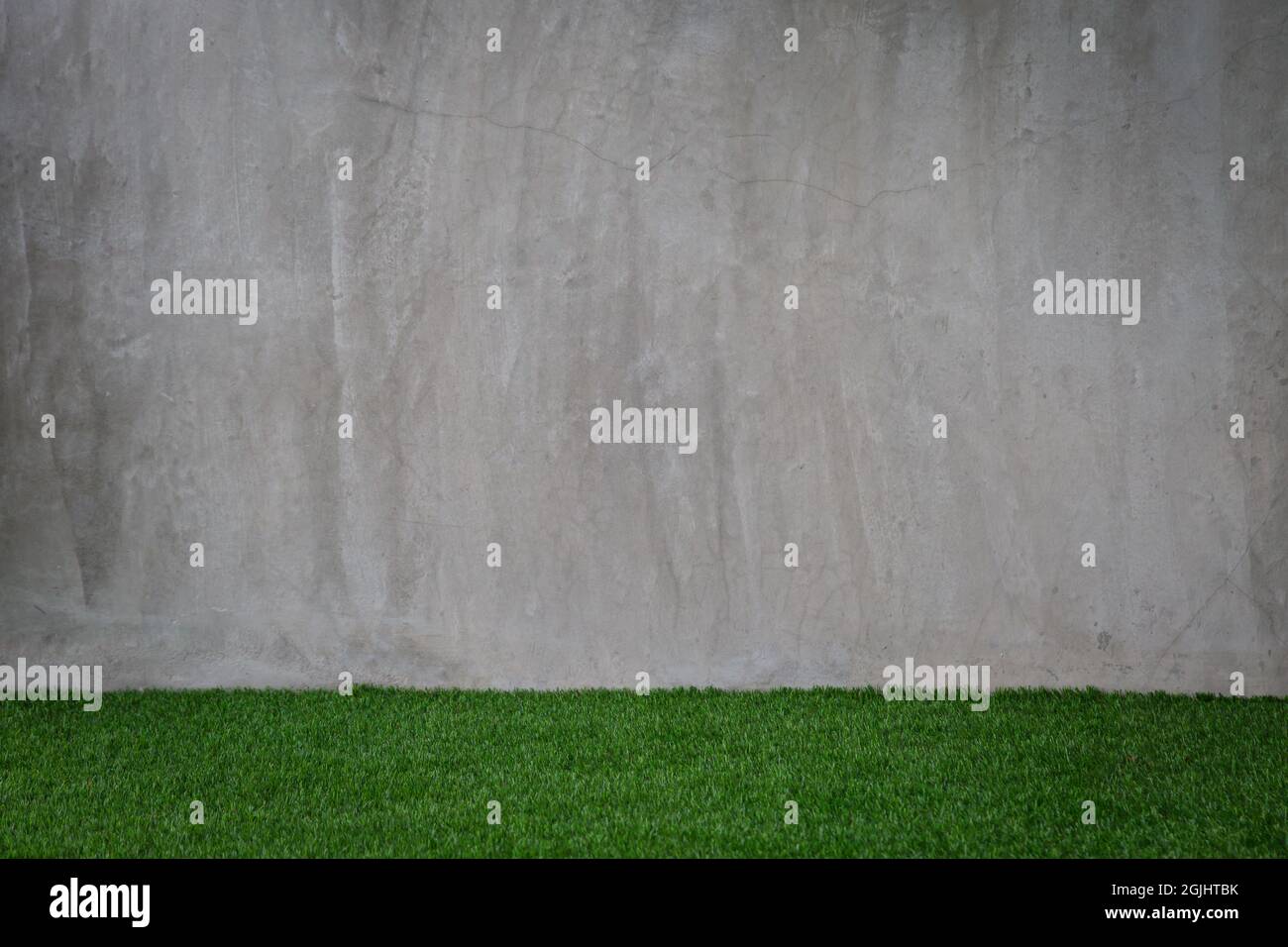 Green grass artificial turf pattern with gray cement wall background ...