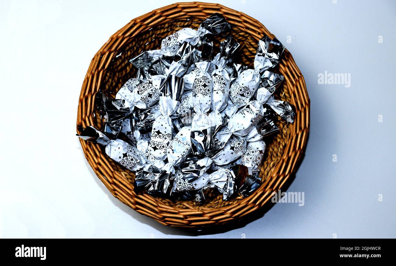 White and silver packaged Christmas chocolate candies in a brown wicker ...