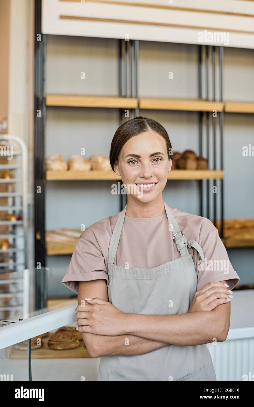 Portrait of happy young Caucasian owner of bakery standing with crossed ...