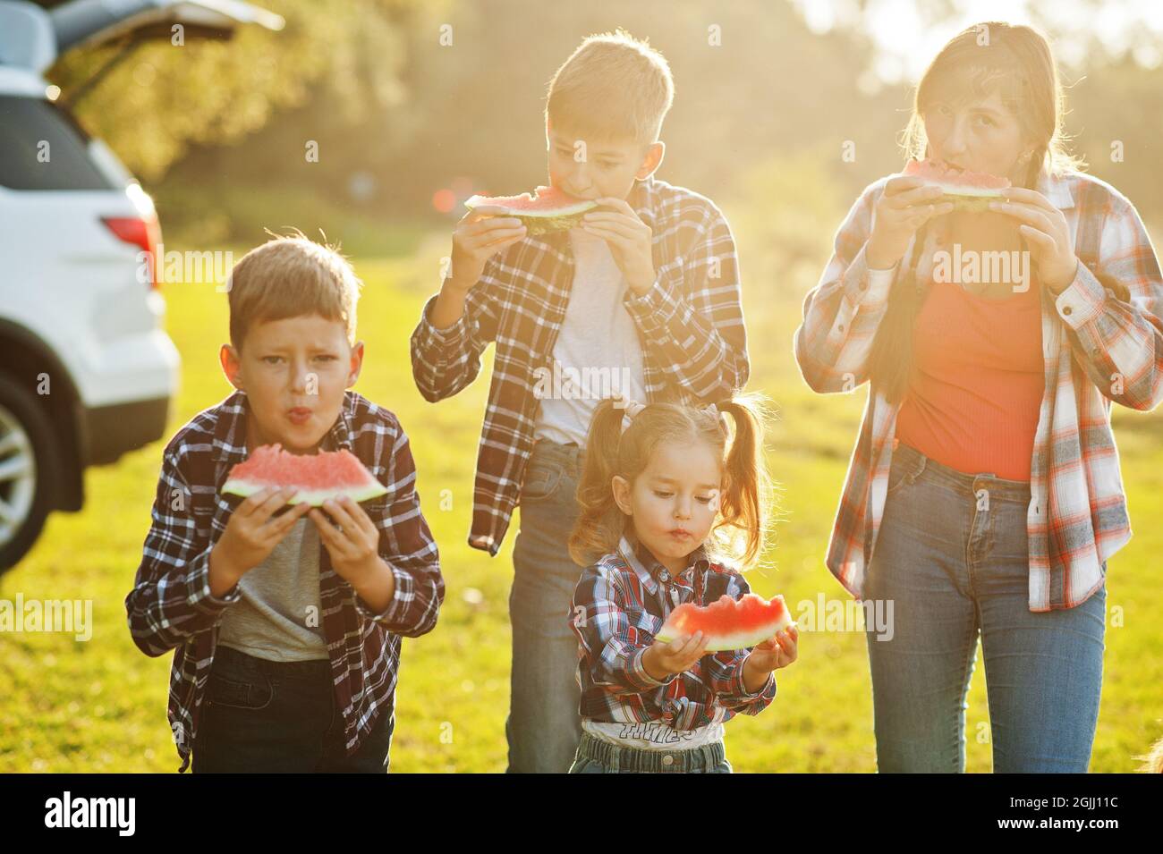 Family spending time together. Three kids with mother eat watermelon ...