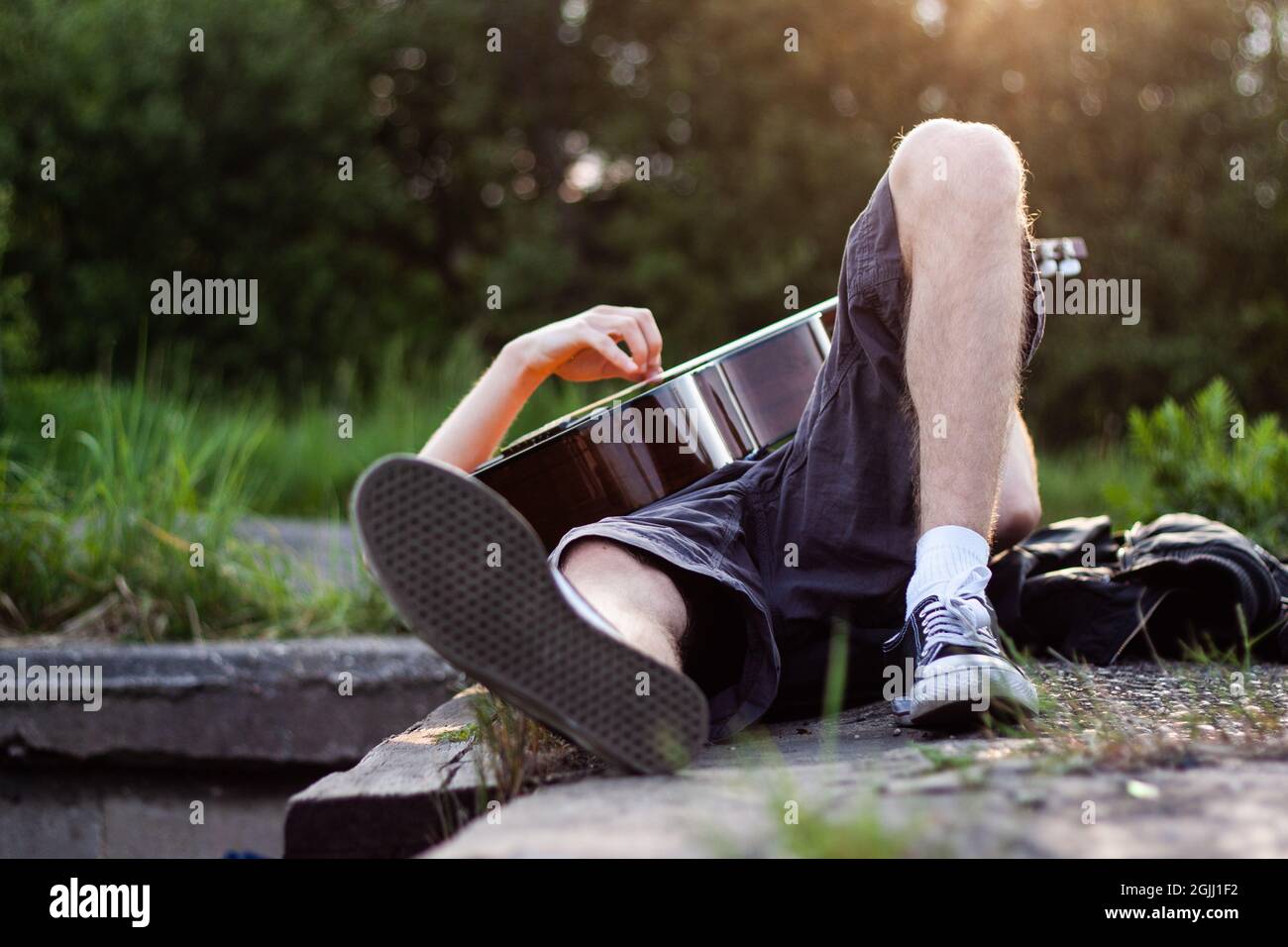 Man playing a guitar laying on his back with feet towards the camera ...