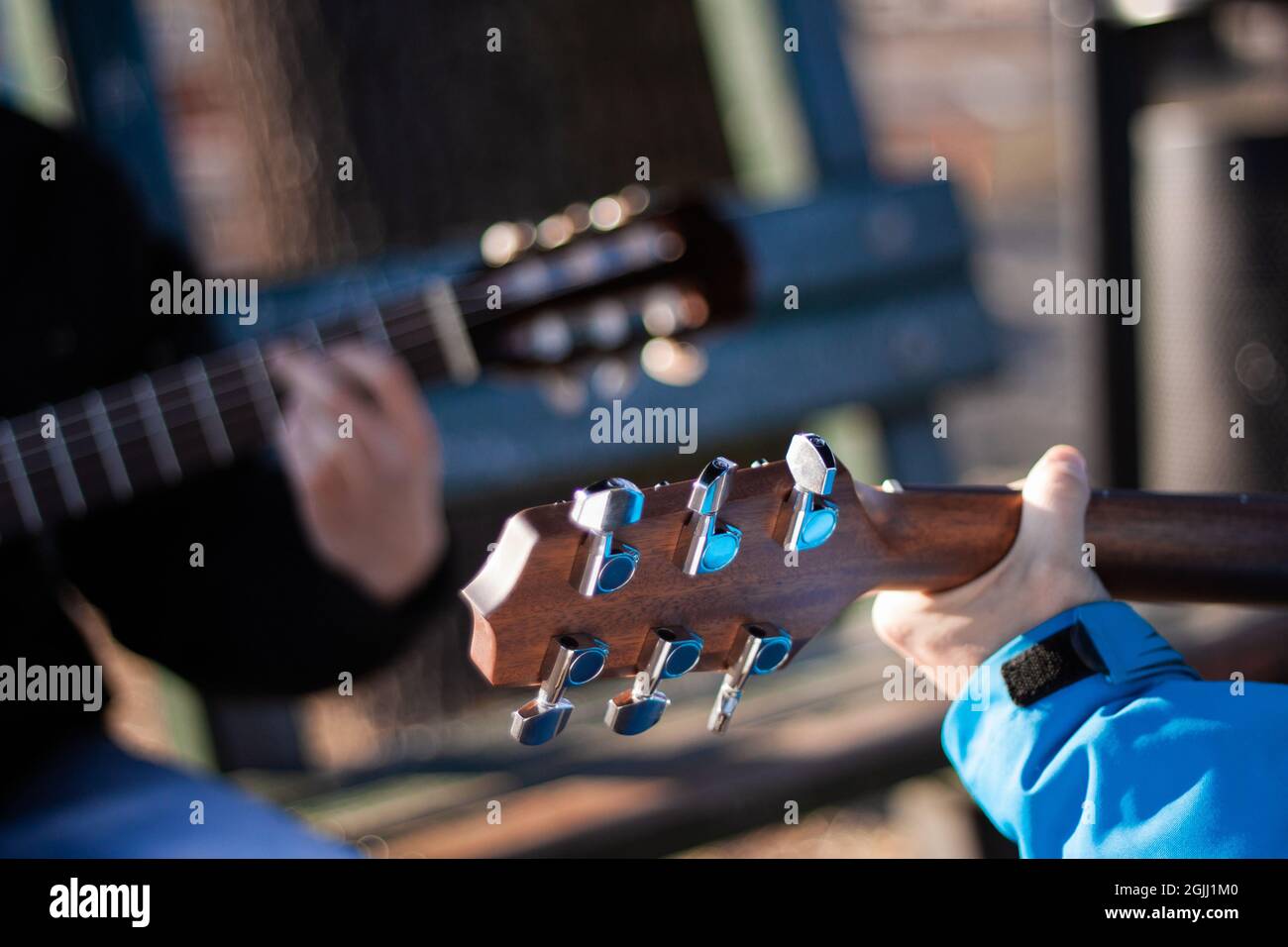 Two men playing a guitar at park close up | Close back view photo of ...