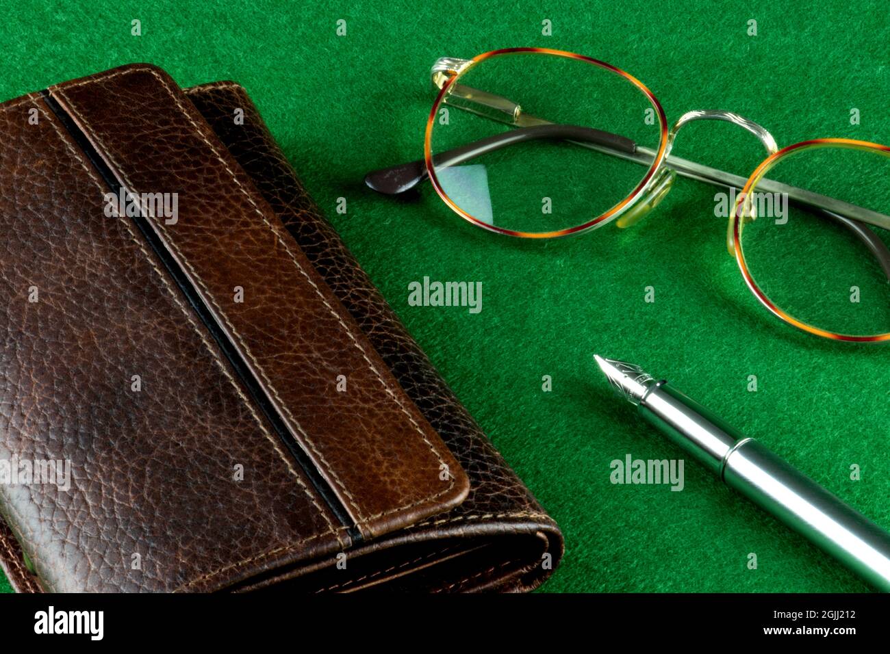 Spectacles fountain pen and leather wallet on a felt covered table ...