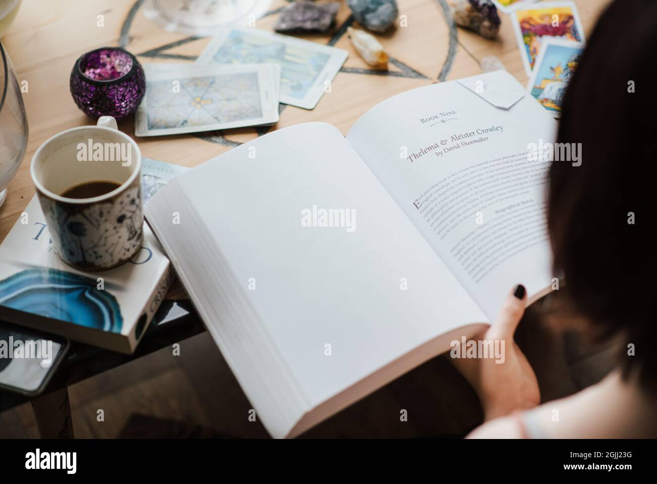Closeup of the girl reading a book surrounded by items for spiritual ...