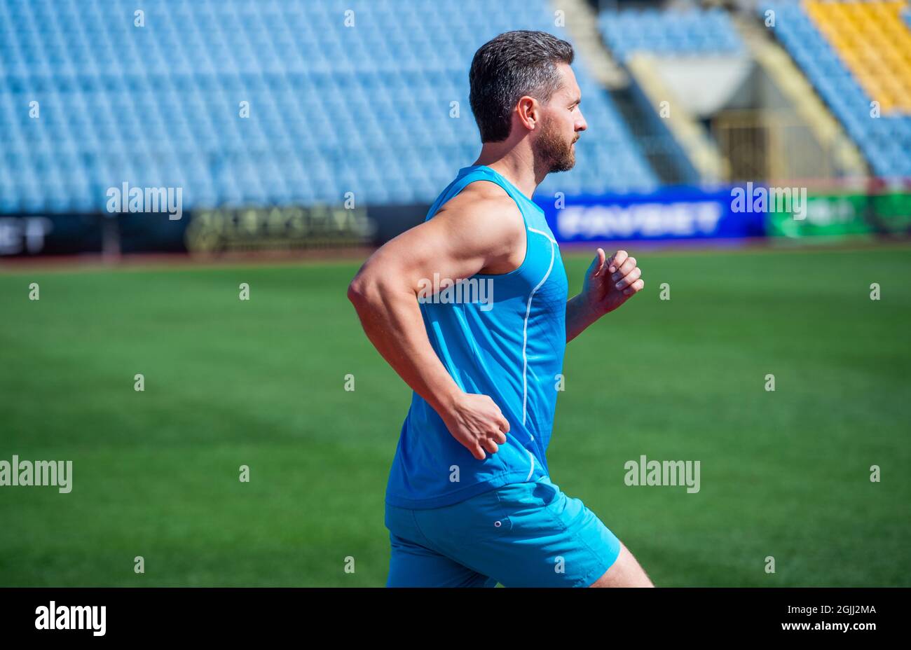 athletic muscular man running in sportswear on stadium track, endurance ...