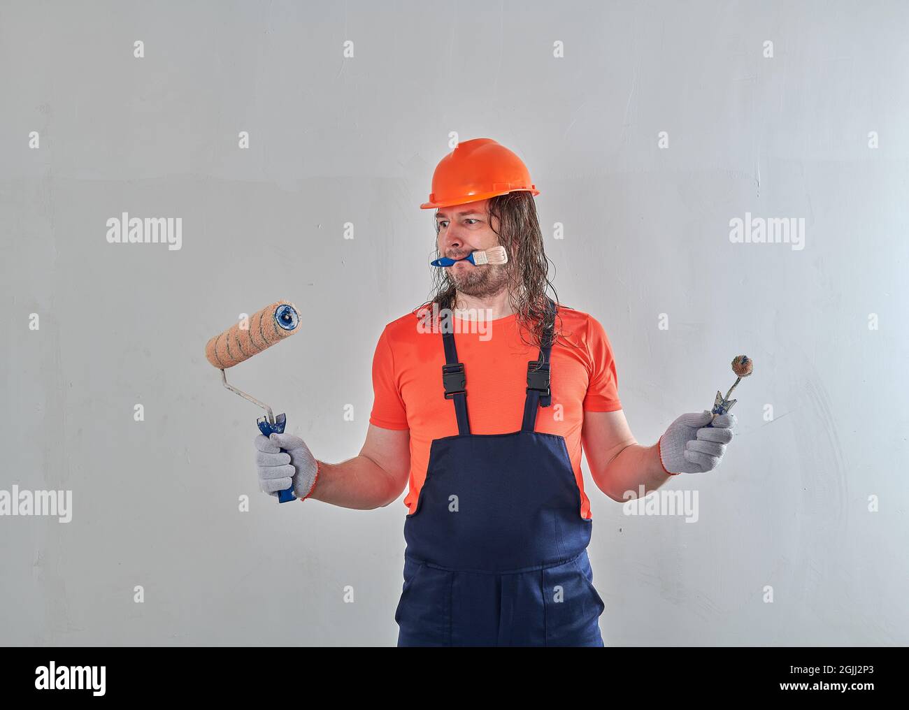 funny repairman with paint rollers and a paintbrush stands Stock Photo ...